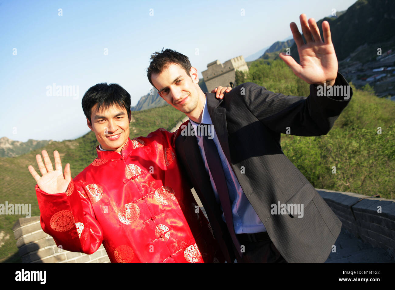 Chinese traditional man and caucasian businessman waving on great wall ...