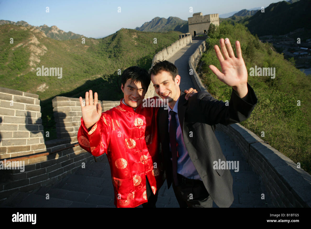 Chinese traditional man and caucasian businessman waving on great wall ...