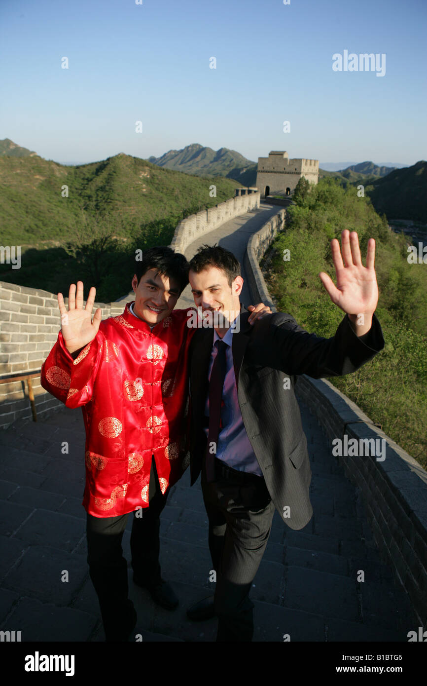 Chinese traditional man and caucasian businessman waving on Great Wall ...