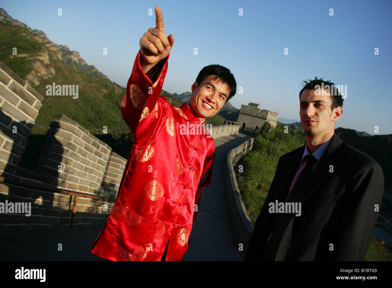 Chinese traditional man and caucasian businessman talking on Great Wall ...