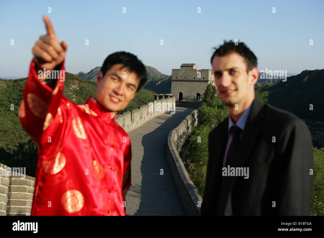 Chinese traditional man and caucasian businessman talking on Great Wall ...
