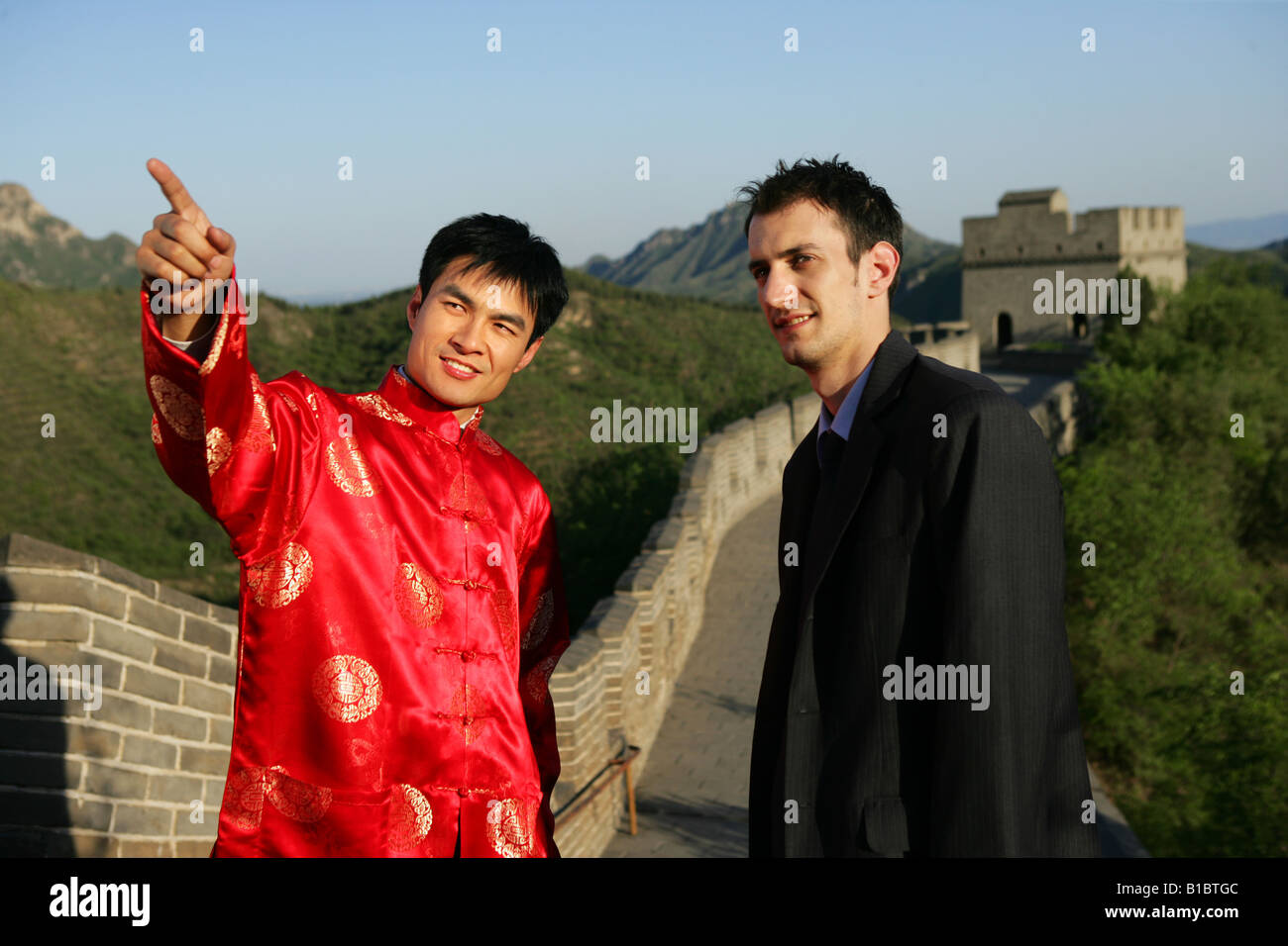 Chinese traditional man and caucasian businessman talking on Great Wall ...