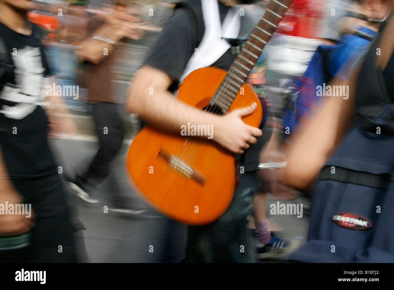 guitar player carrying instrument in crowd in street in town Stock ...