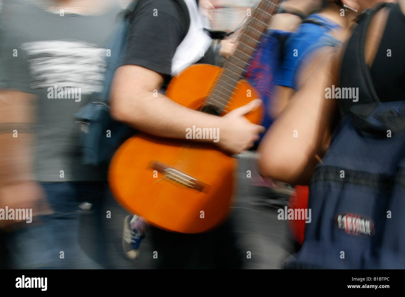 guitar player carrying instrument in crowd in street in town Stock ...