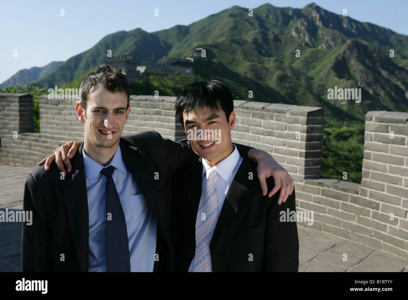 caucasian businessman and Chinese businessman standing on Great Wall ...