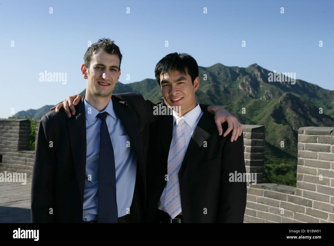 caucasian businessman and Chinese businessman standing on Great Wall ...