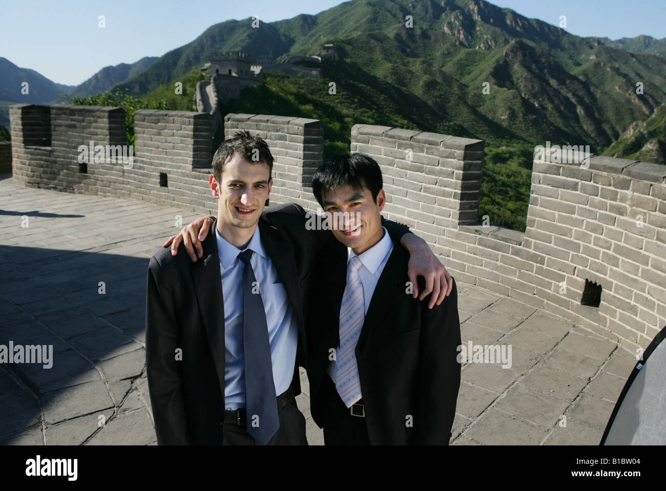 caucasian businessman and Chinese businessman standing on Great Wall ...