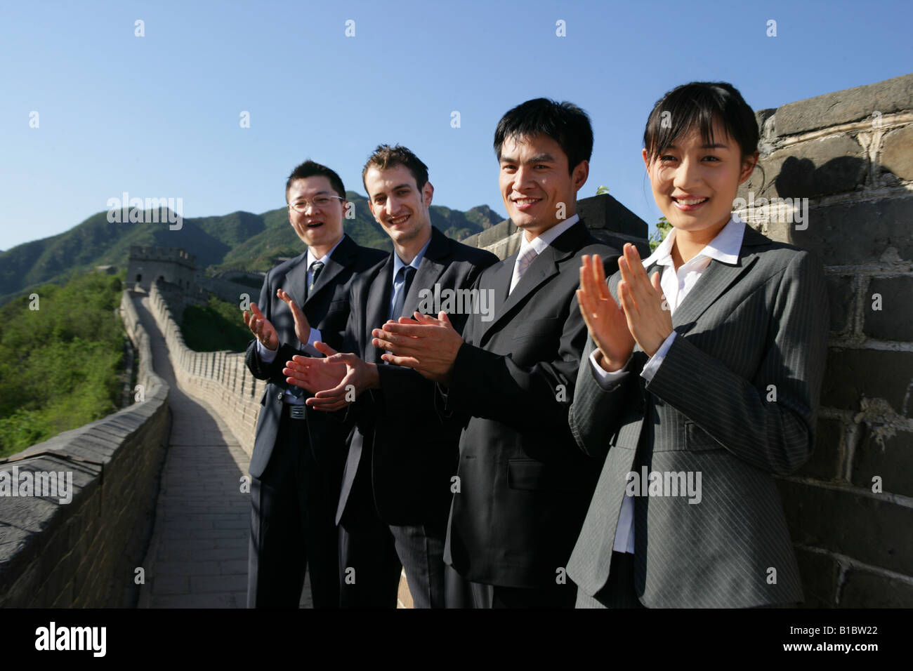 three businessmen and one businesswoman clapping on Great Wall,Beijing ...