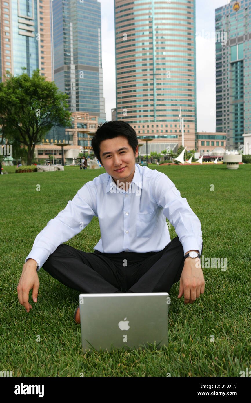 one businessman using a laptop on lawn outside office buildings in ...