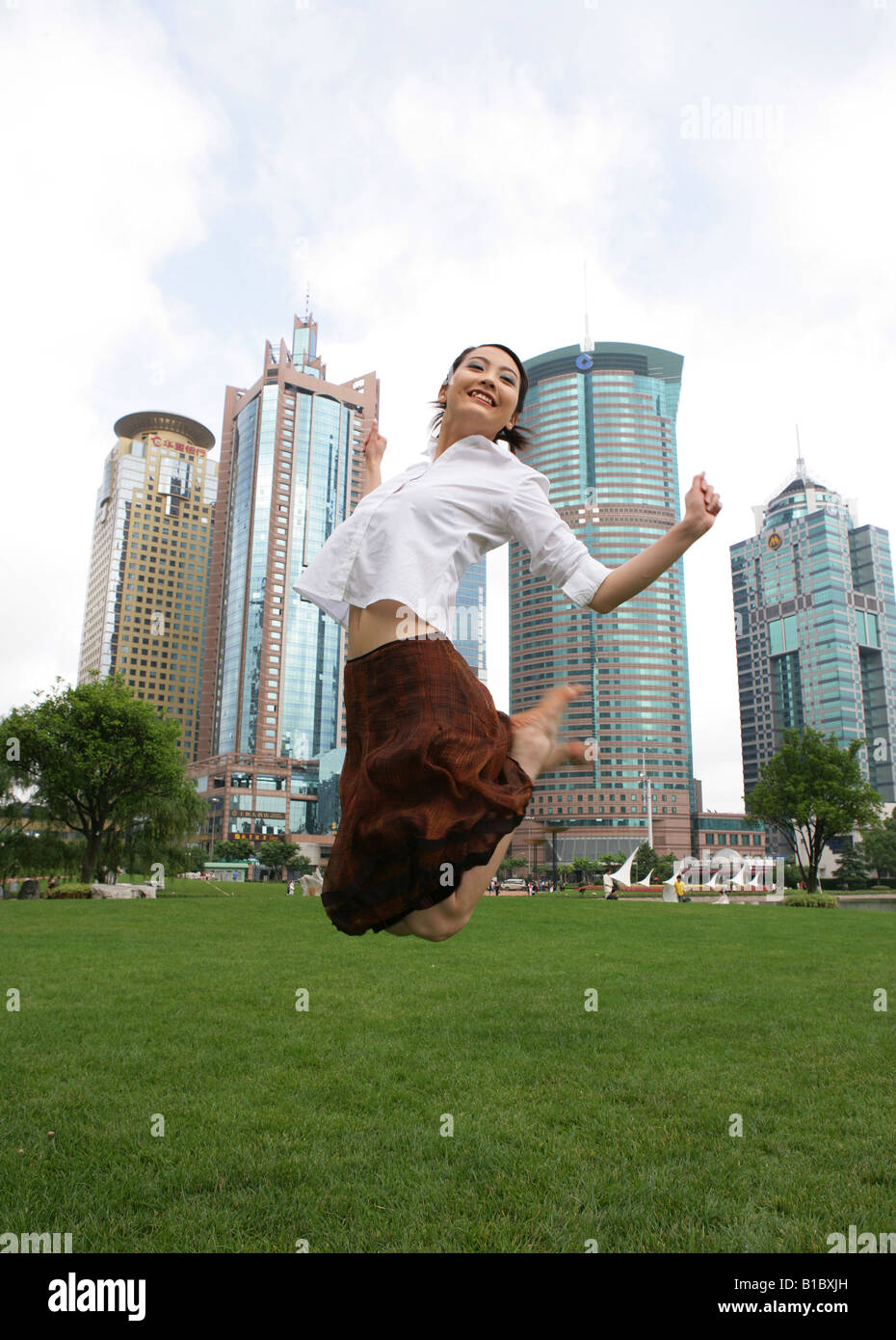 one businesswoman jumping on the lawn outside office buildings in ...