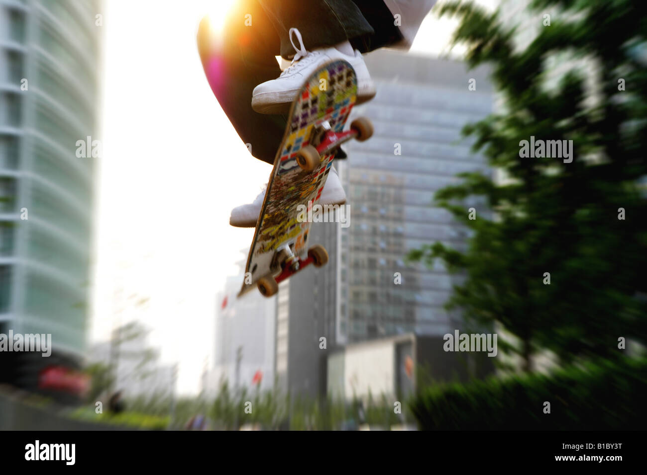legs of young man skateboarding on square beside office buildings ...