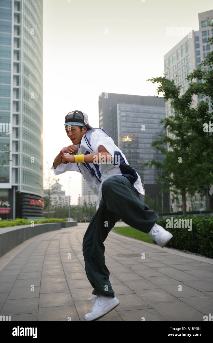 young man performing posture of combative sport on square beside office ...