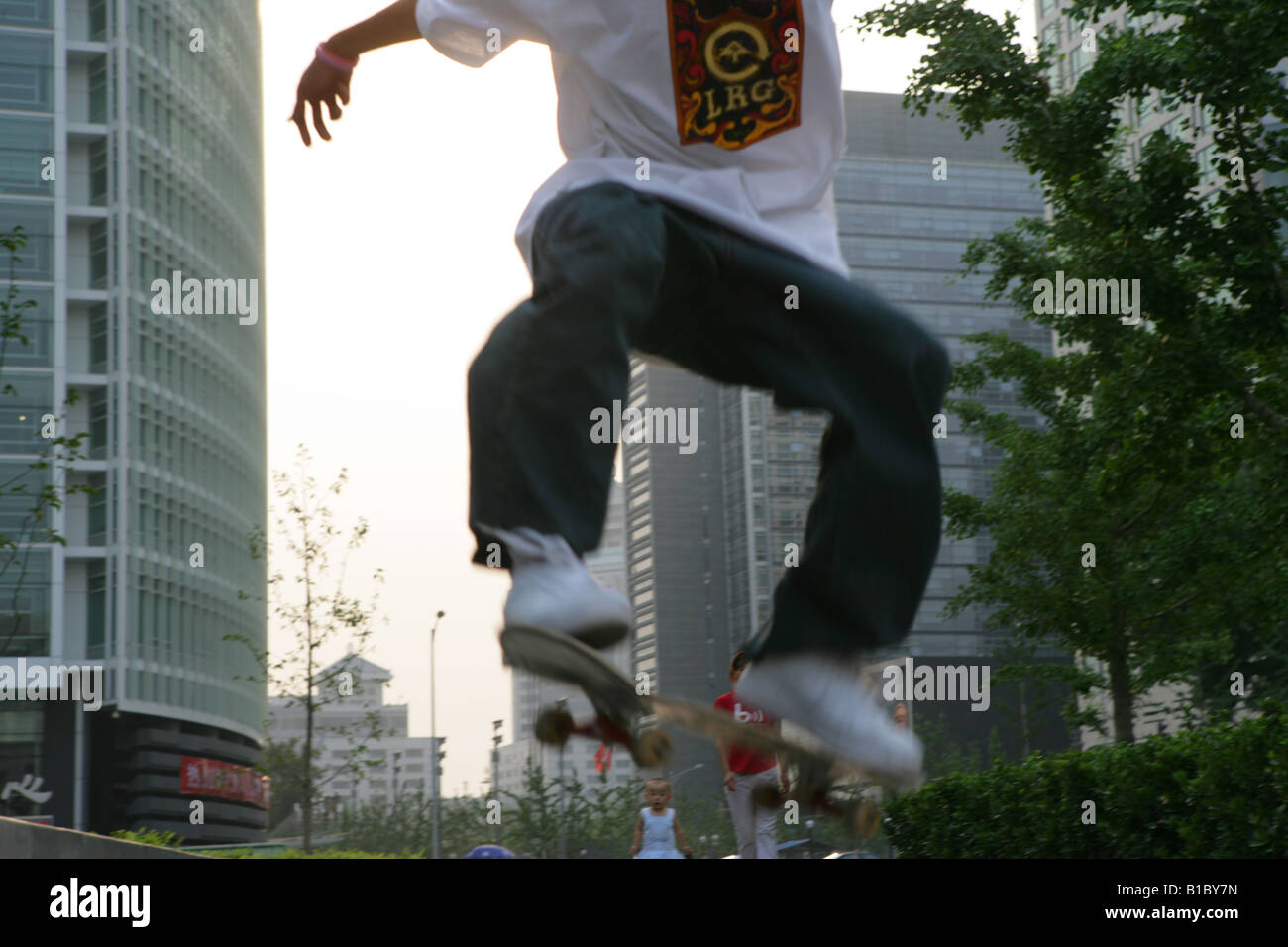 leg of young man skateboarding on square beside office buildings ...