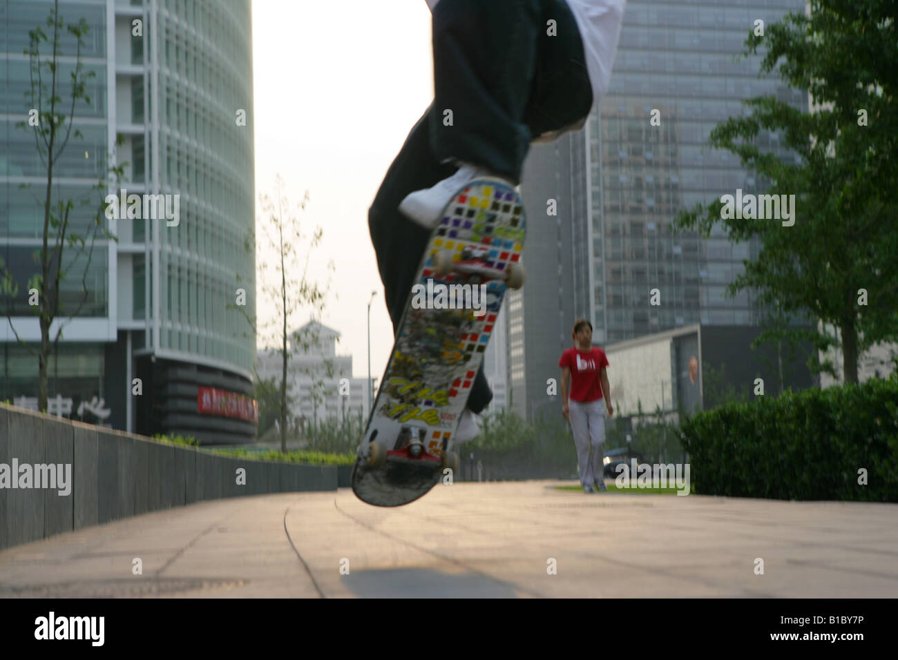 leg of young man skateboarding on square beside office buildings ...