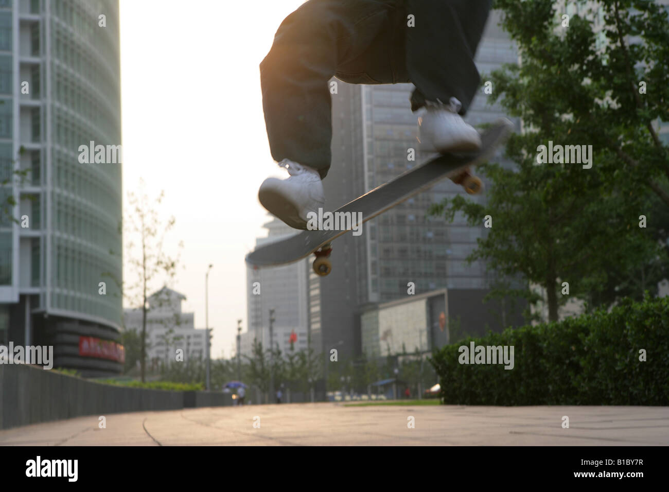 leg of young man skateboarding on square beside office buildings ...