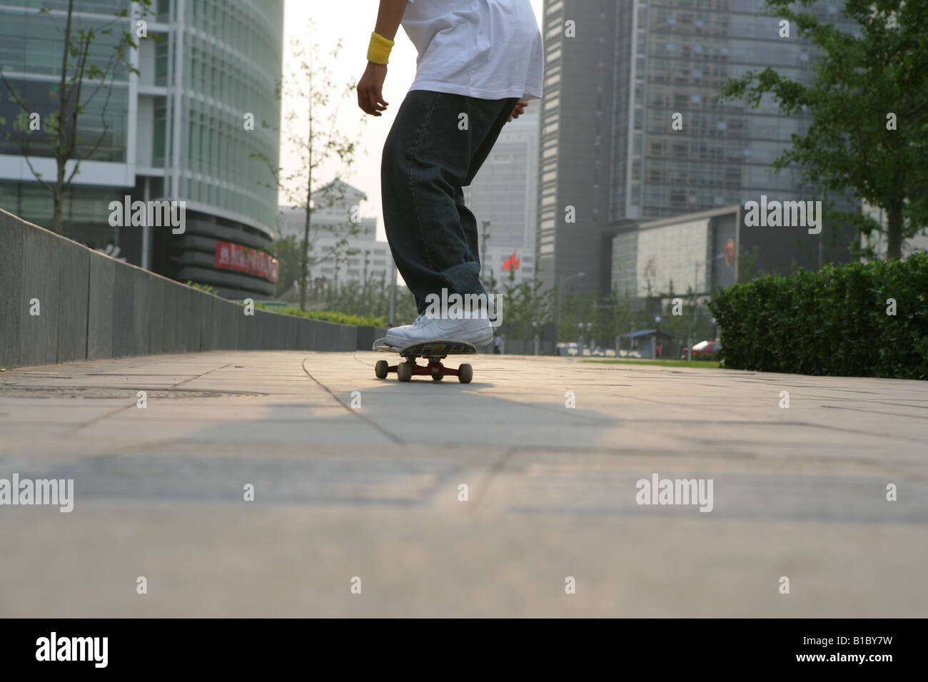 leg of young man skateboarding on square beside office buildings ...