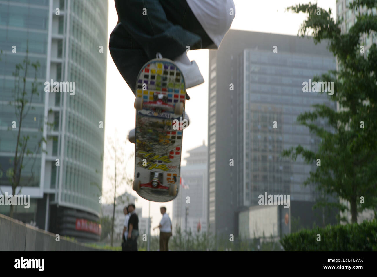 leg of young man skateboarding on square beside office buildings ...