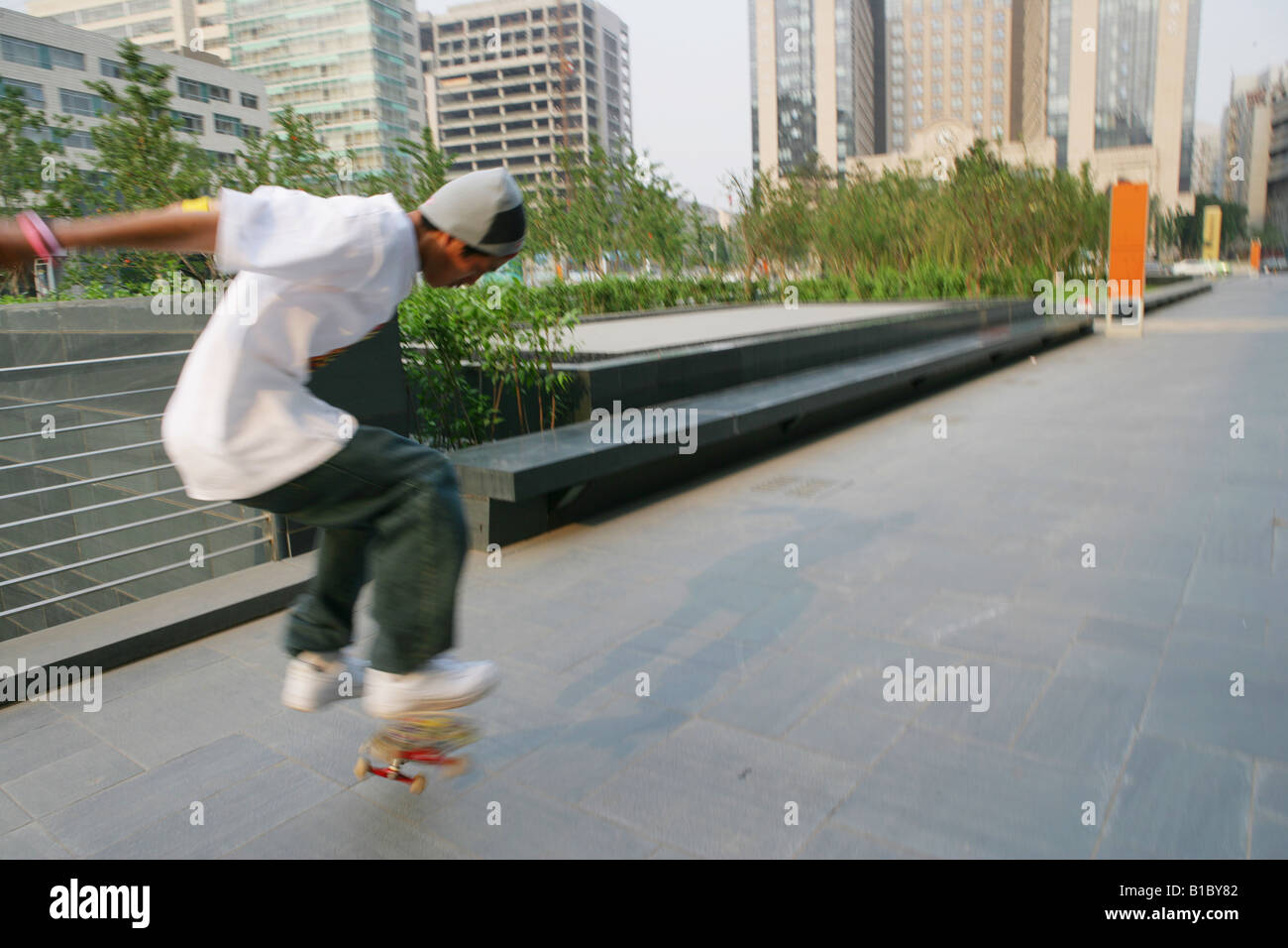 young man skateboarding on square beside office buildings,Beijing,China ...