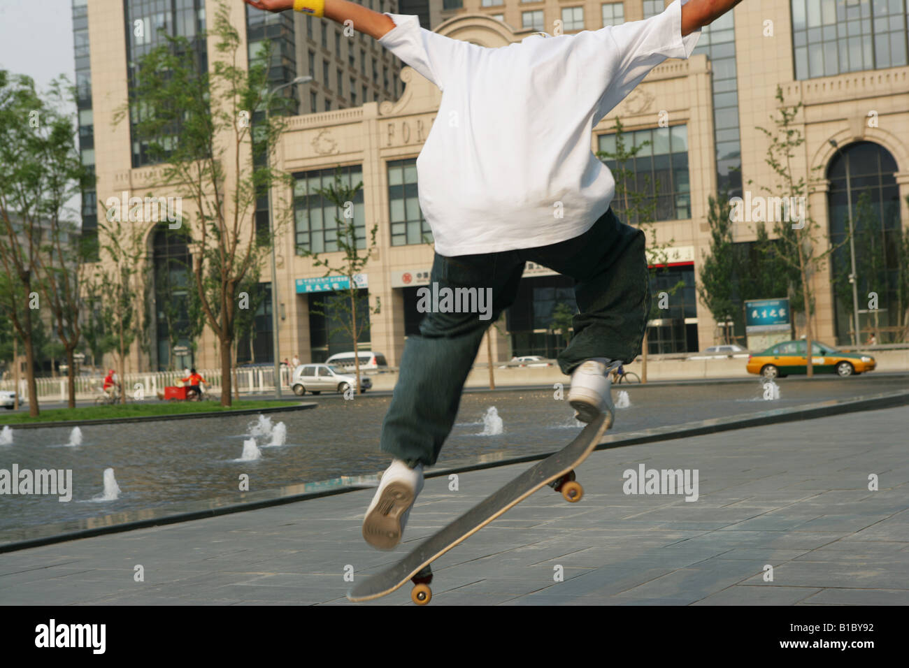 young man skateboarding on square beside office buildings,Beijing,China ...