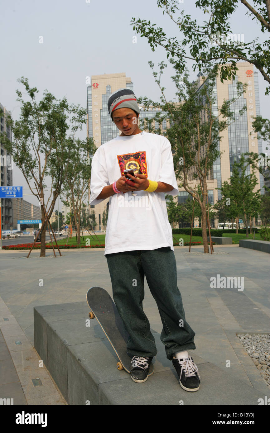 young man text messaging with skateboard Stock Photo - Alamy