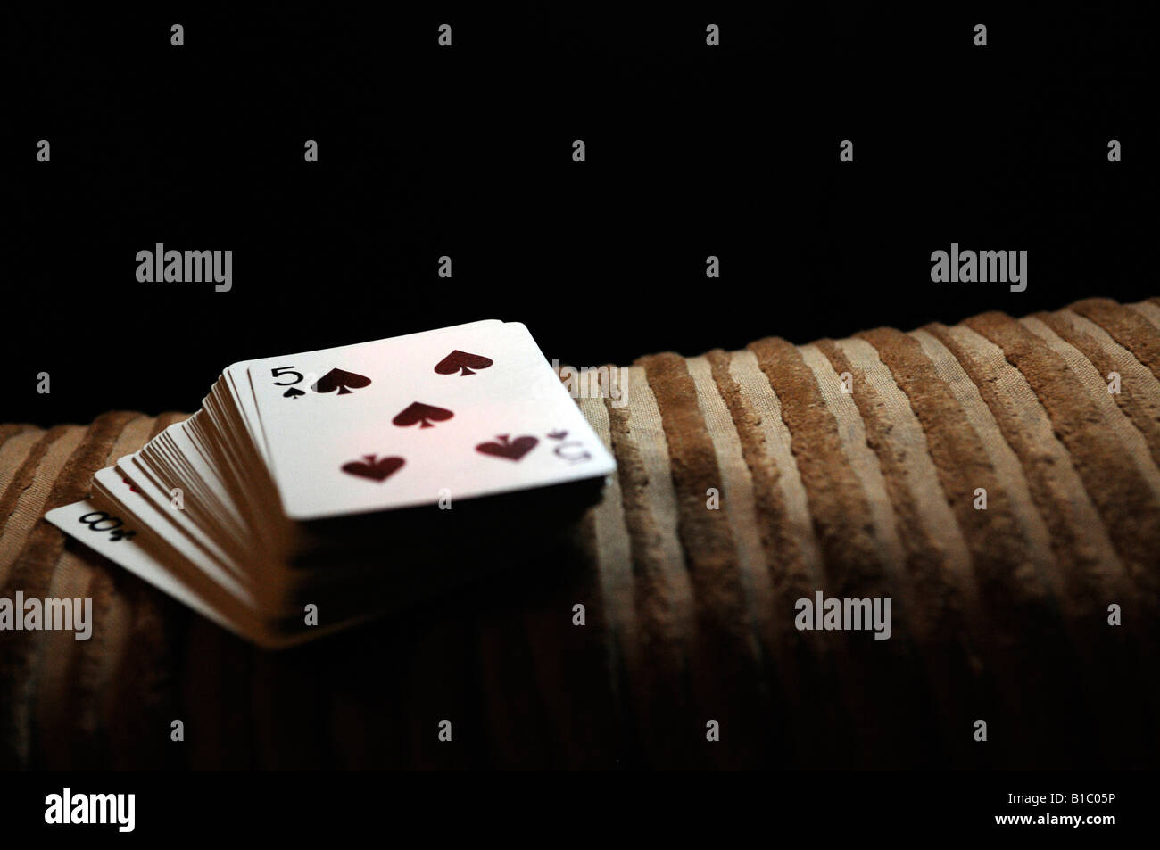 Playing cards on arm of 70s couch lit by TV Stock Photo - Alamy
