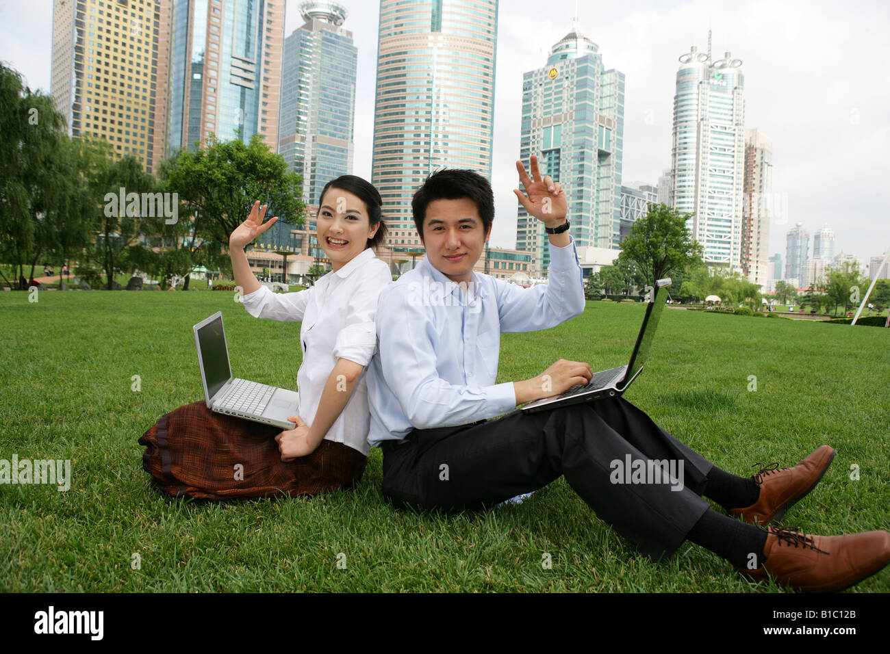 one businessman and one businesswoman gesturing V sign outside office ...
