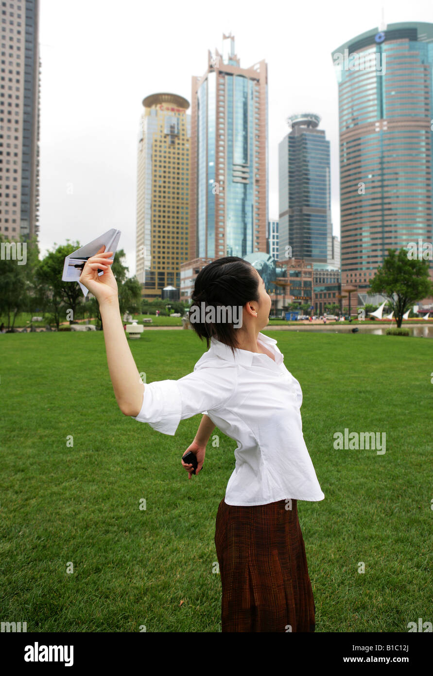 one businesswoman playing a paper airplane outside office buildings in ...