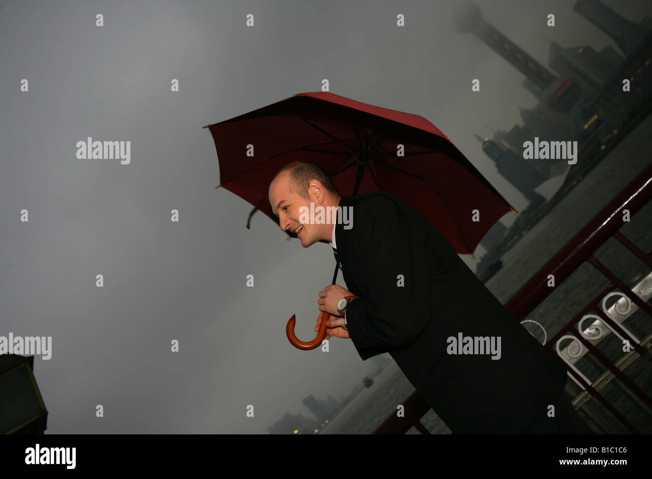 one foreign businessman smiling while holding an opened umbrella at the ...