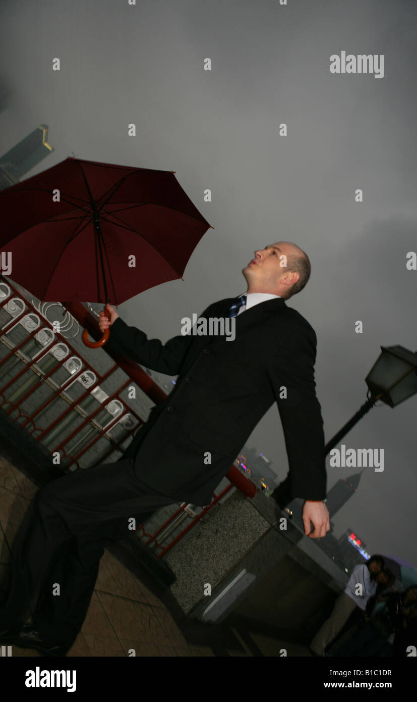 one foreign businessman walking with an opened umbrella at the Bund ...