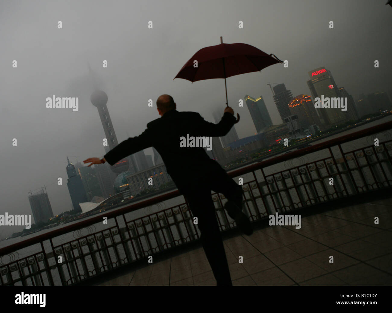 one foreign businessman jumping with an opened umbrella at the Bund ...