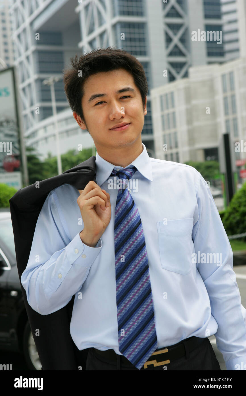 one businessman smiling with coat on his shoulder outside office ...