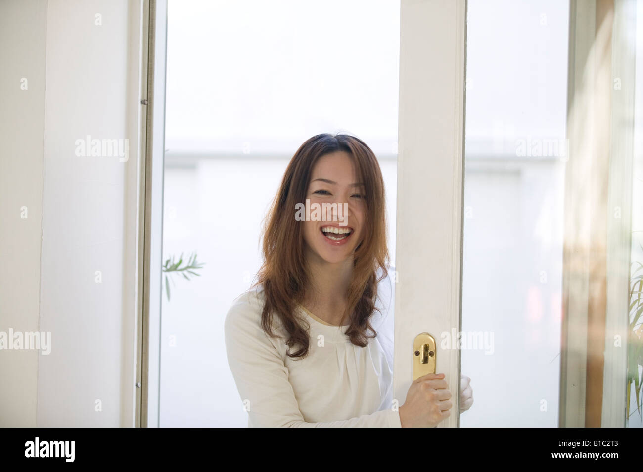 Young woman opening door Stock Photo - Alamy
