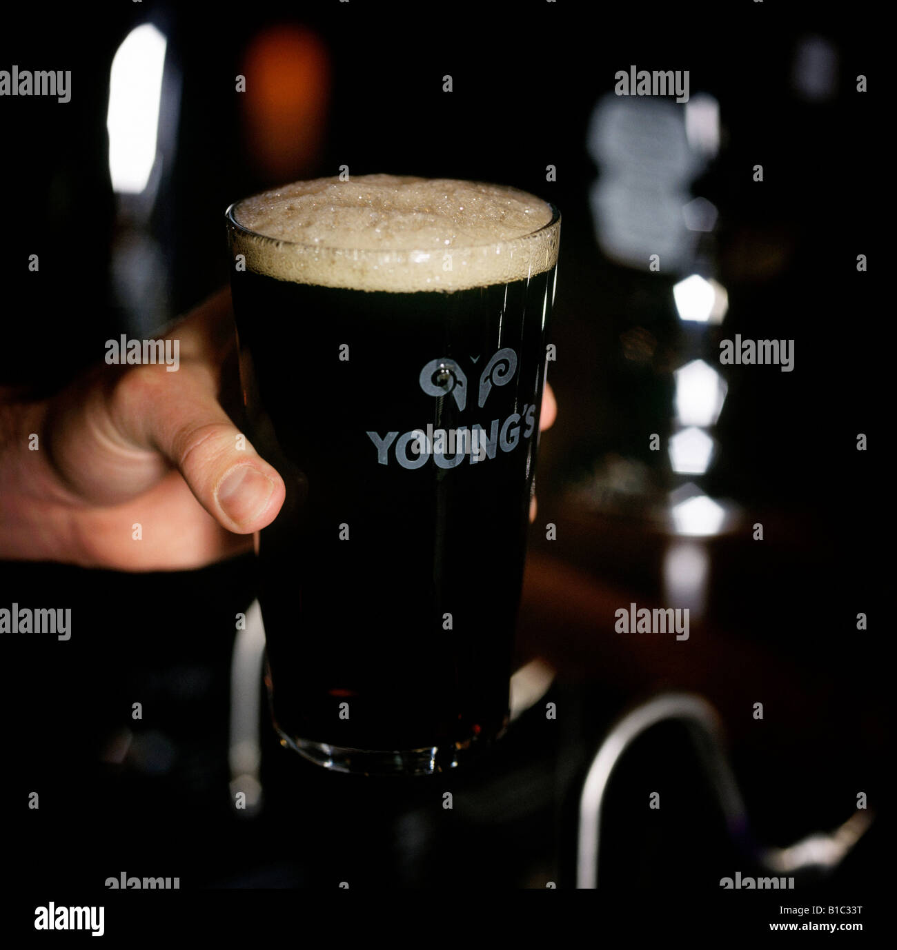 a hand holding a pint of Youngs bitter Stock Photo - Alamy