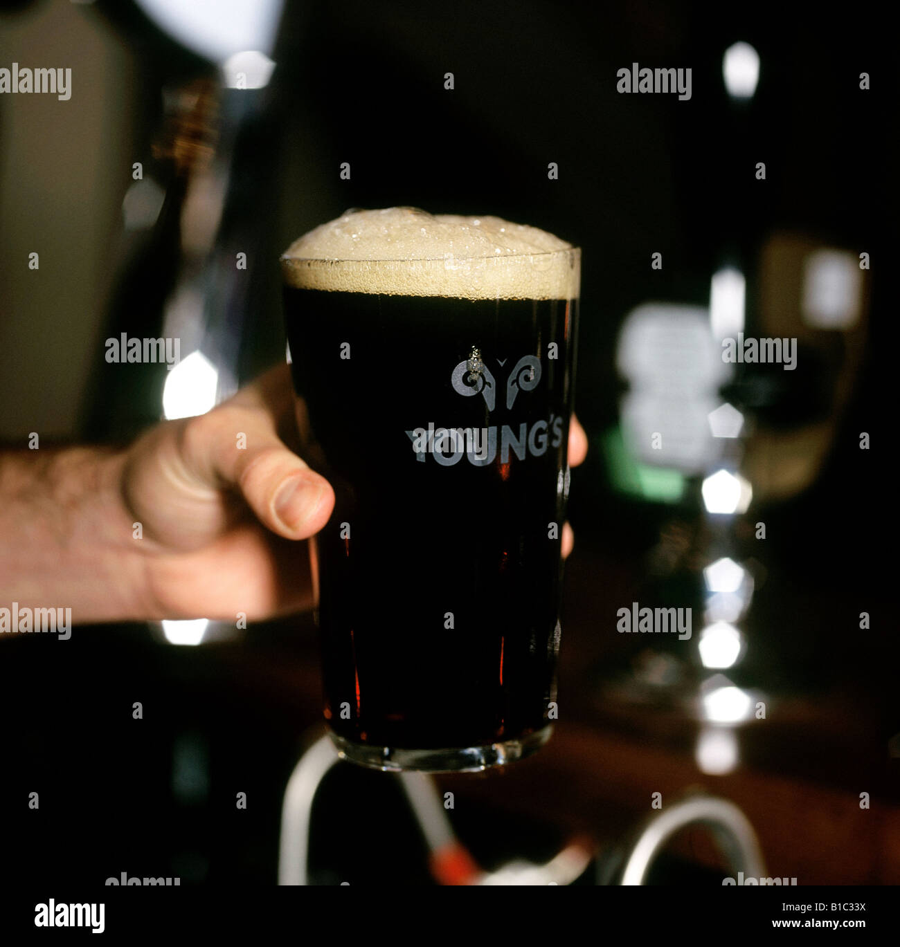 a hand holding a pint of Youngs bitter Stock Photo - Alamy