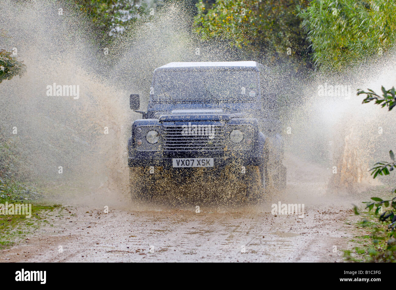 land rover defender off roading down a muddy lane in the uk countryside ...