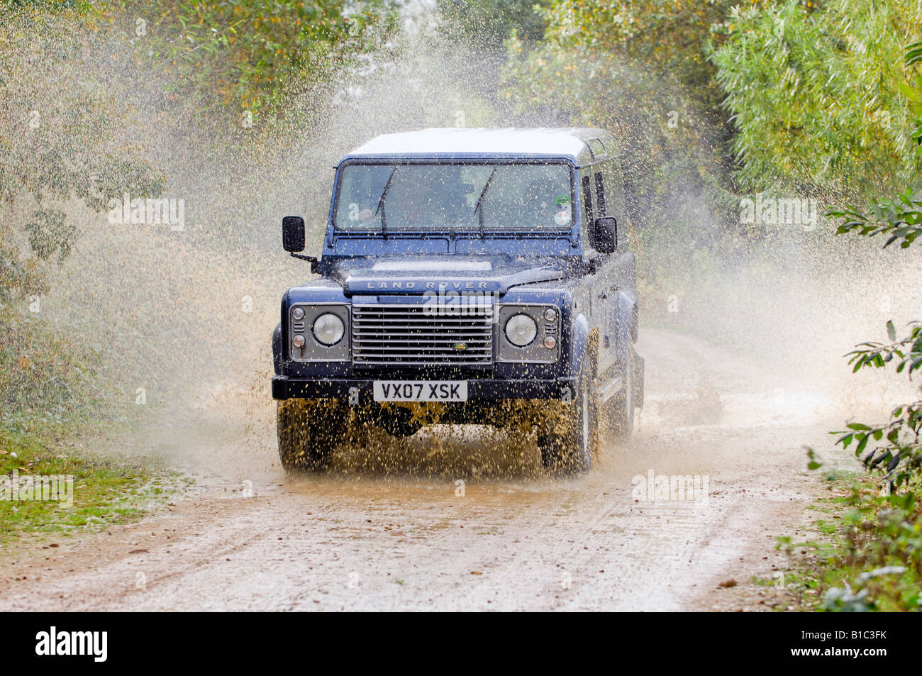 land rover defender off roading down a muddy lane in the uk countryside ...