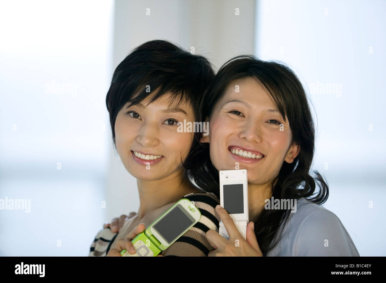 Two women holding mobile phones Stock Photo - Alamy