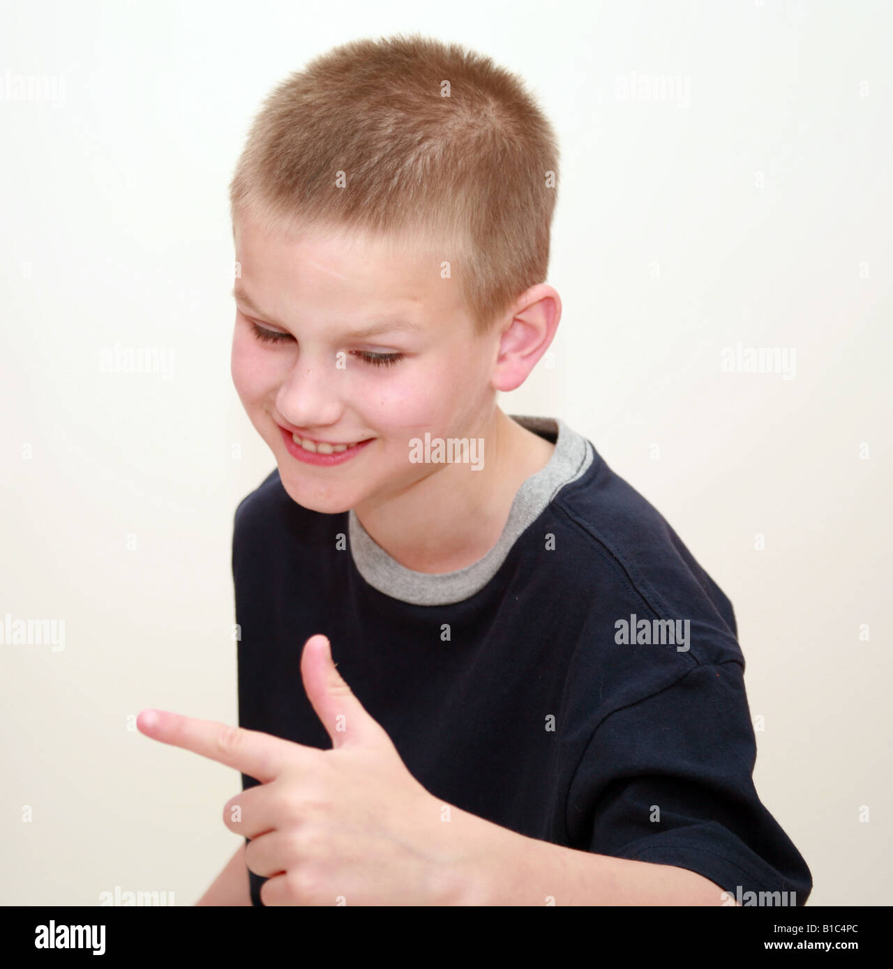 Boy in studio smiling and making a funny face and pointing his hand ...