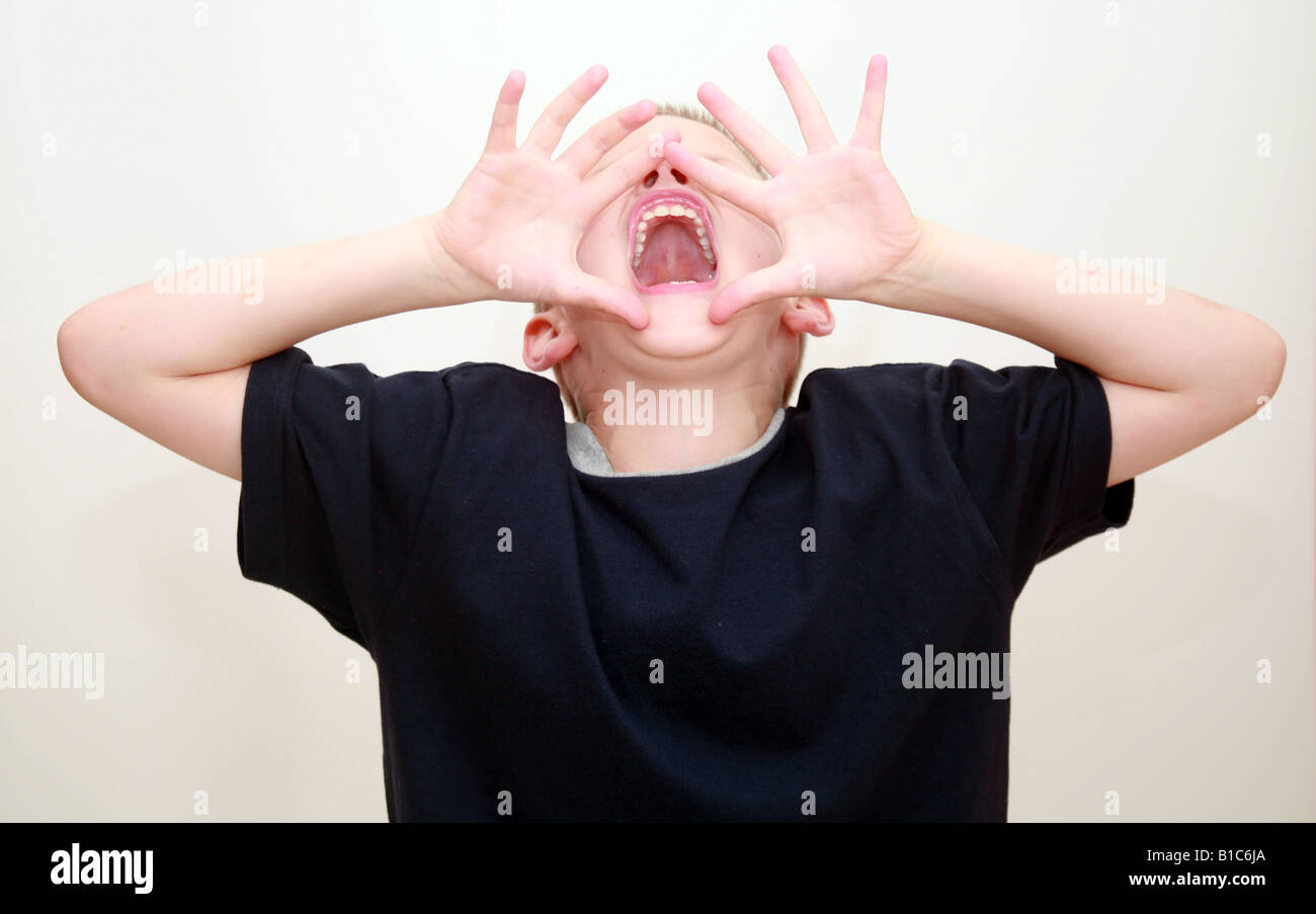 Boy in studio with hands to mouth and shouting loudly Stock Photo - Alamy