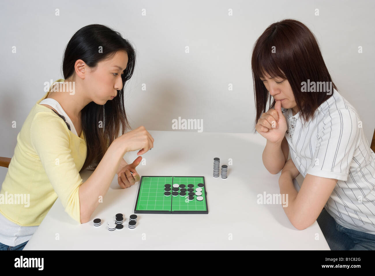 Two young women playing Othello game Stock Photo - Alamy