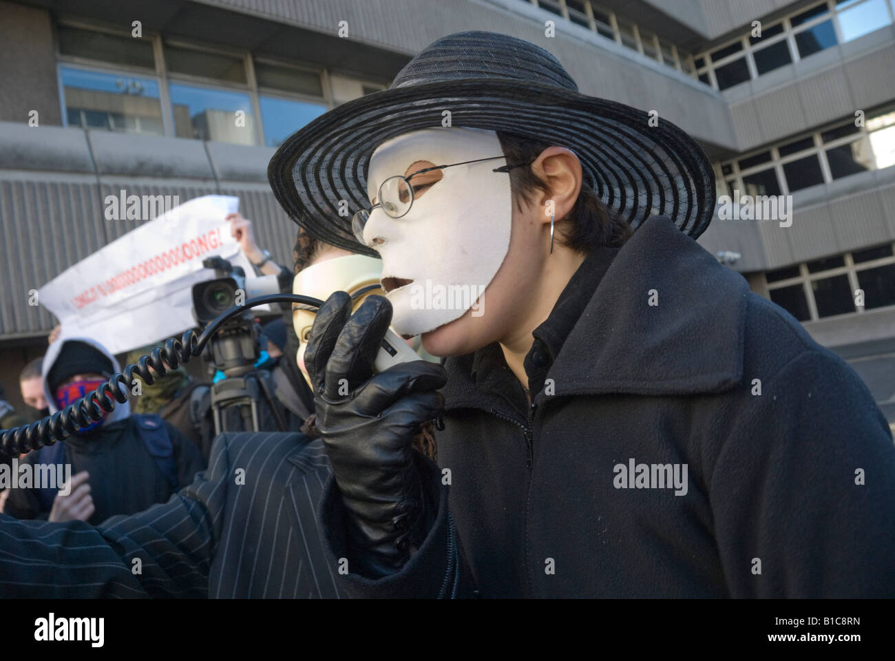 'Anonymous' woman protester in mask speaks into microphone opposite ...
