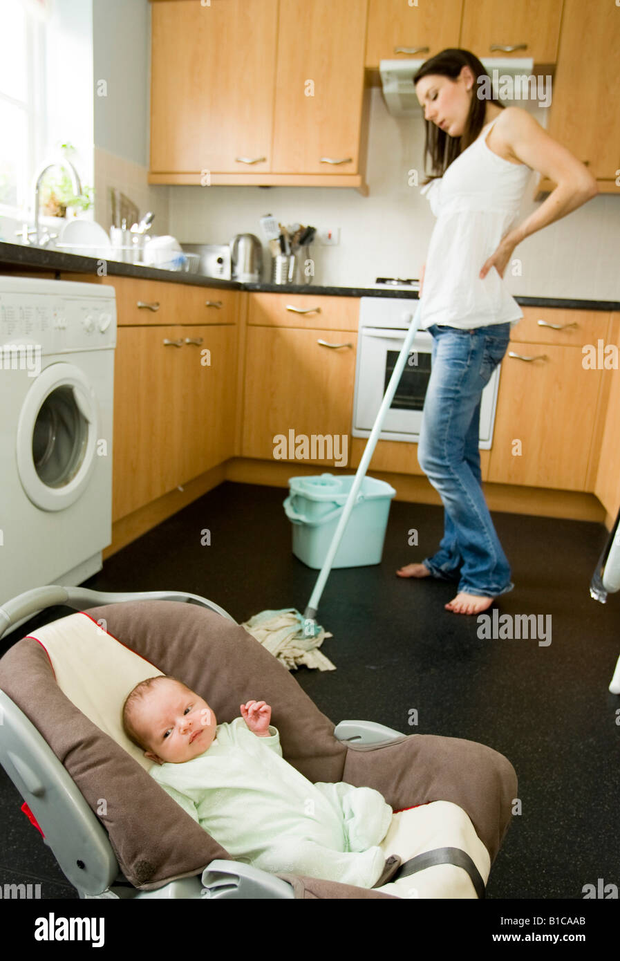 Woman cleaning floor with baby in foreground Stock Photo - Alamy
