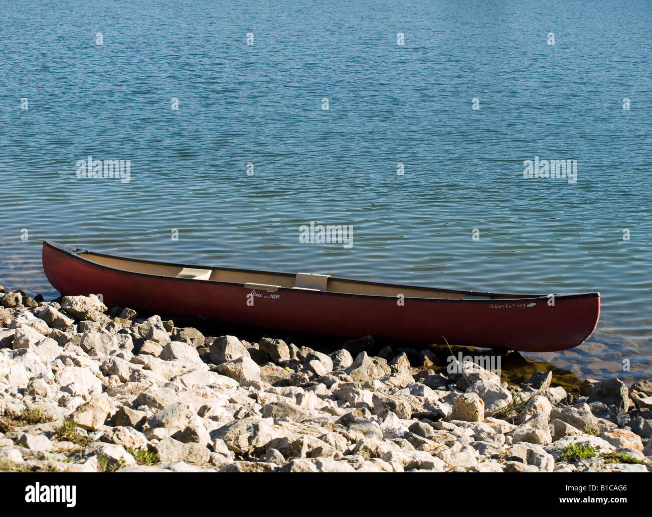 Empty red canoe at the edge of clean blue water Stock Photo - Alamy
