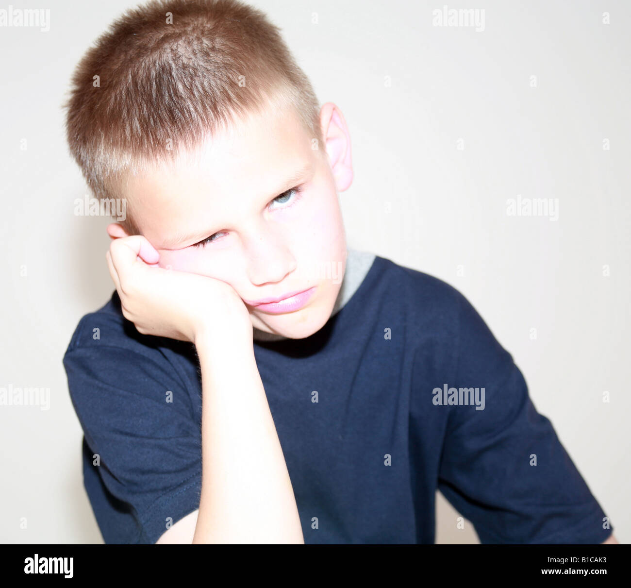 Boy in studio with head on hand looking bored Stock Photo - Alamy