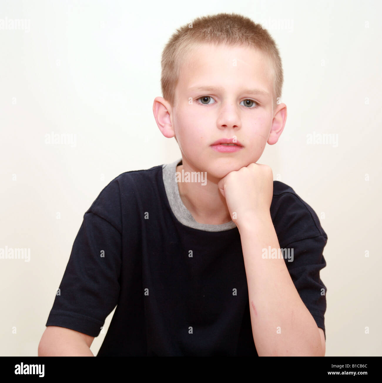 Boy in studio with head on hand looking interested Stock Photo - Alamy