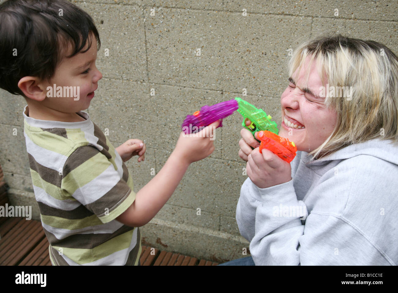Mother and child playing with water guns Stock Photo - Alamy