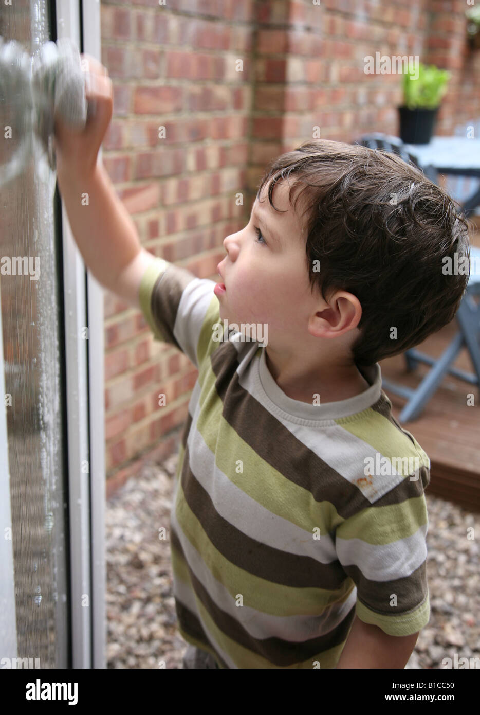 Toddler helping with the housework by cleaning the windows Stock Photo ...