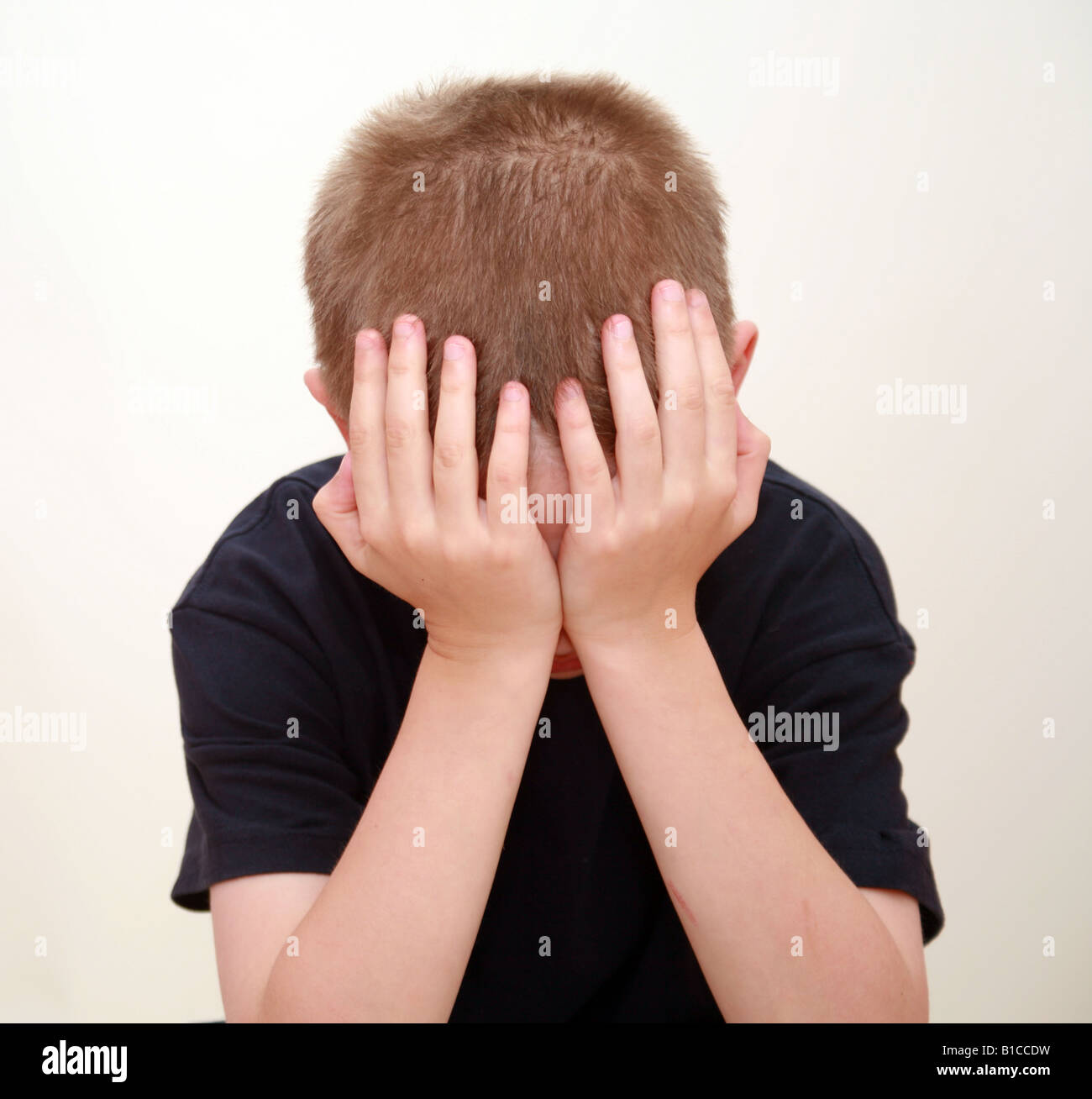 Boy in studio with hands over face crying Stock Photo - Alamy