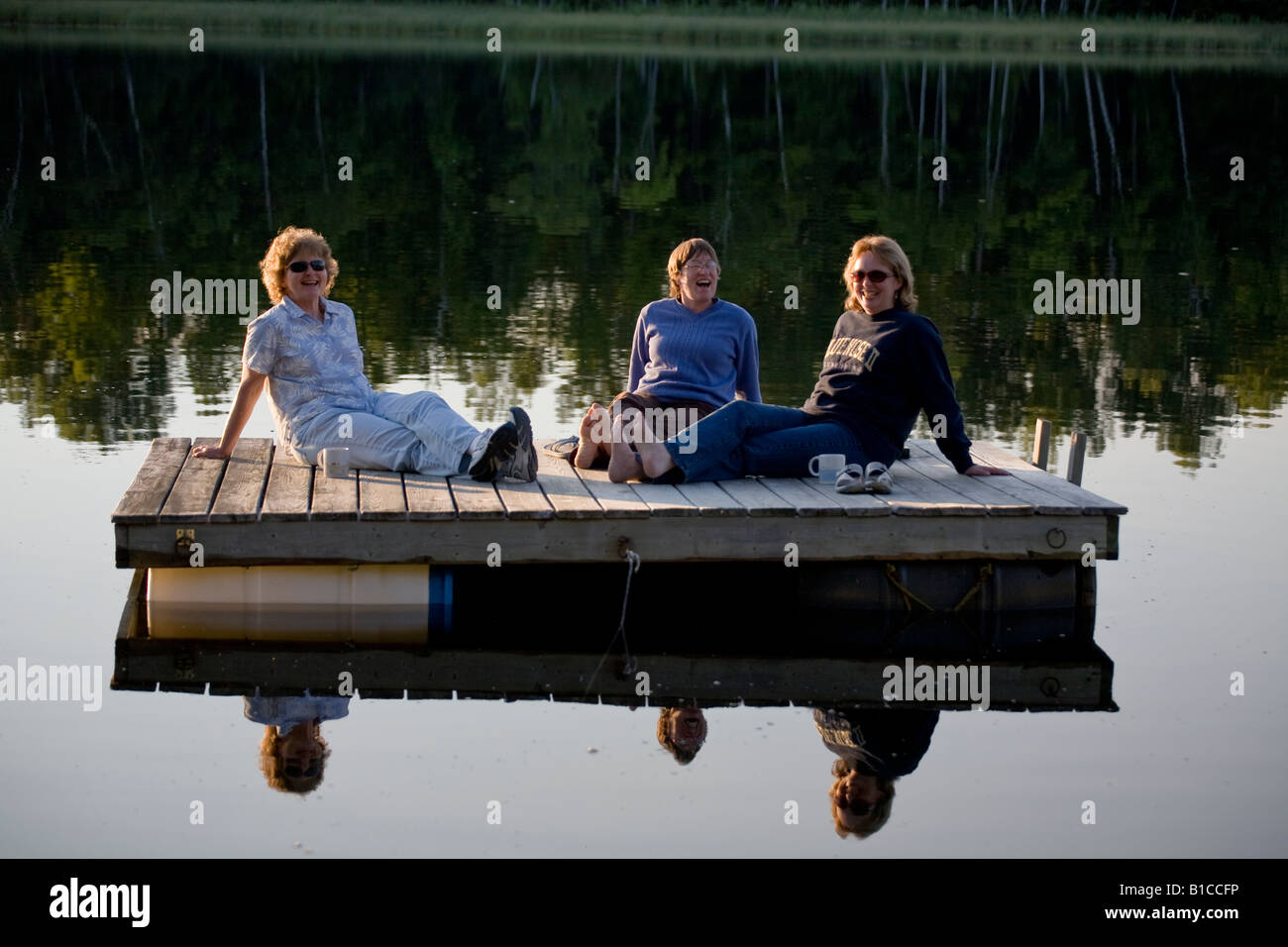 Girls Evening Out. Three woman relaxing on a detached floating dock at ...