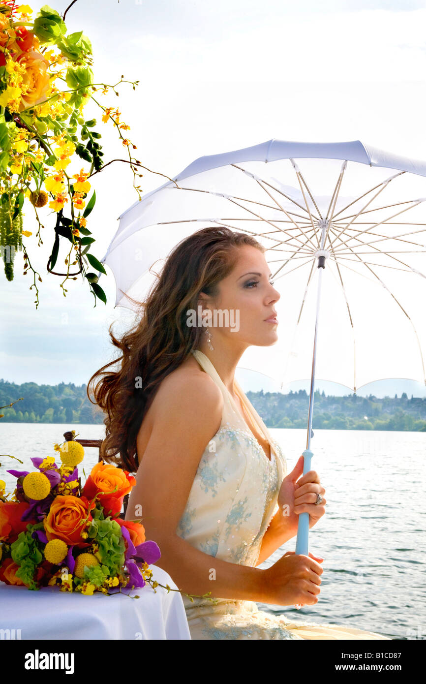 Bride wearing a white gown holding a parasol by the water Stock Photo ...